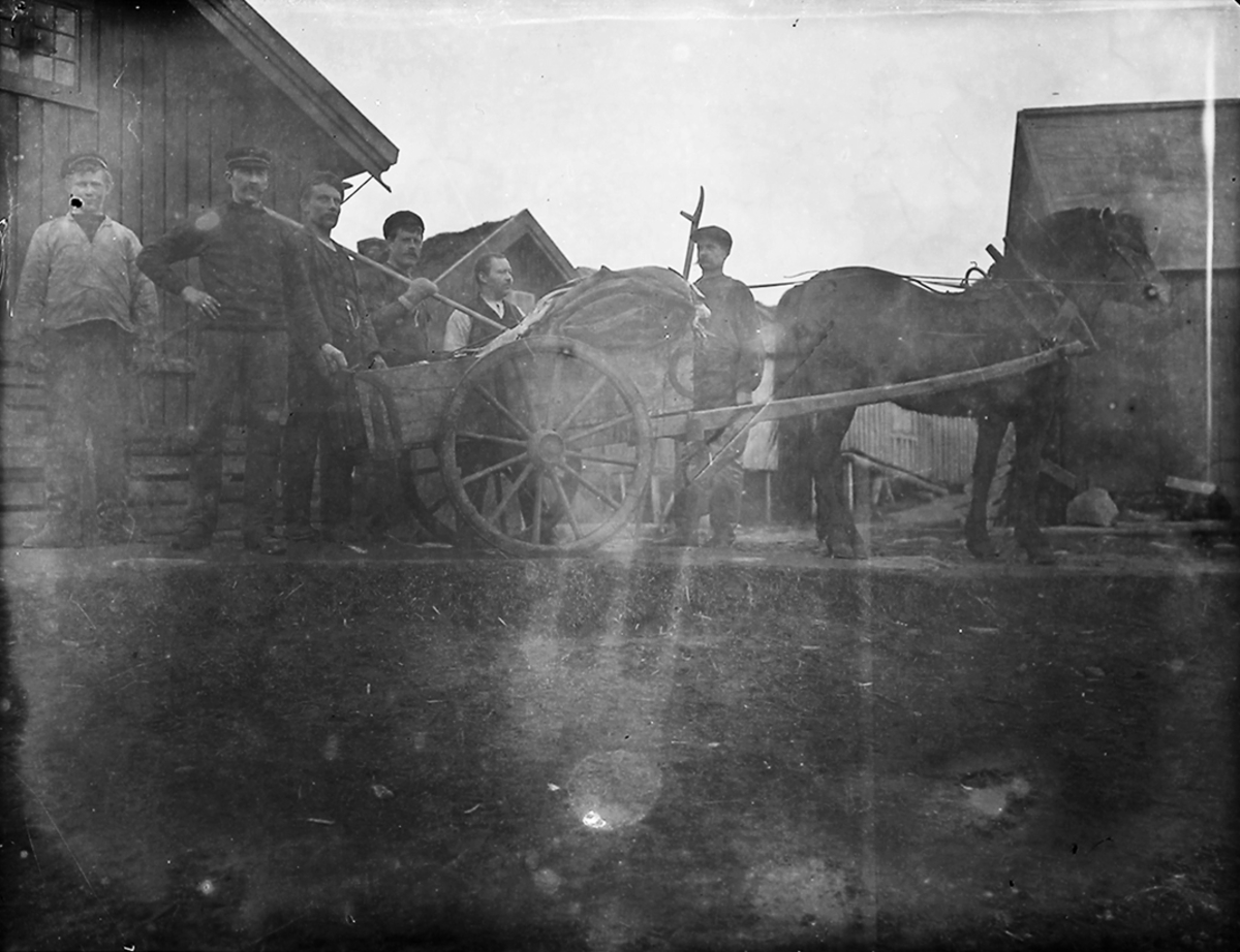 Gruppebilde. 6 menn med hest og vogn.Det ligger fisk i vogna.1 mann med uniformslue. Oppsynsmann ...