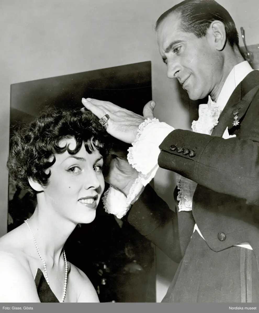 Man i frack, skjorta med krås och ring, fixar till frisyren på kvinna ...