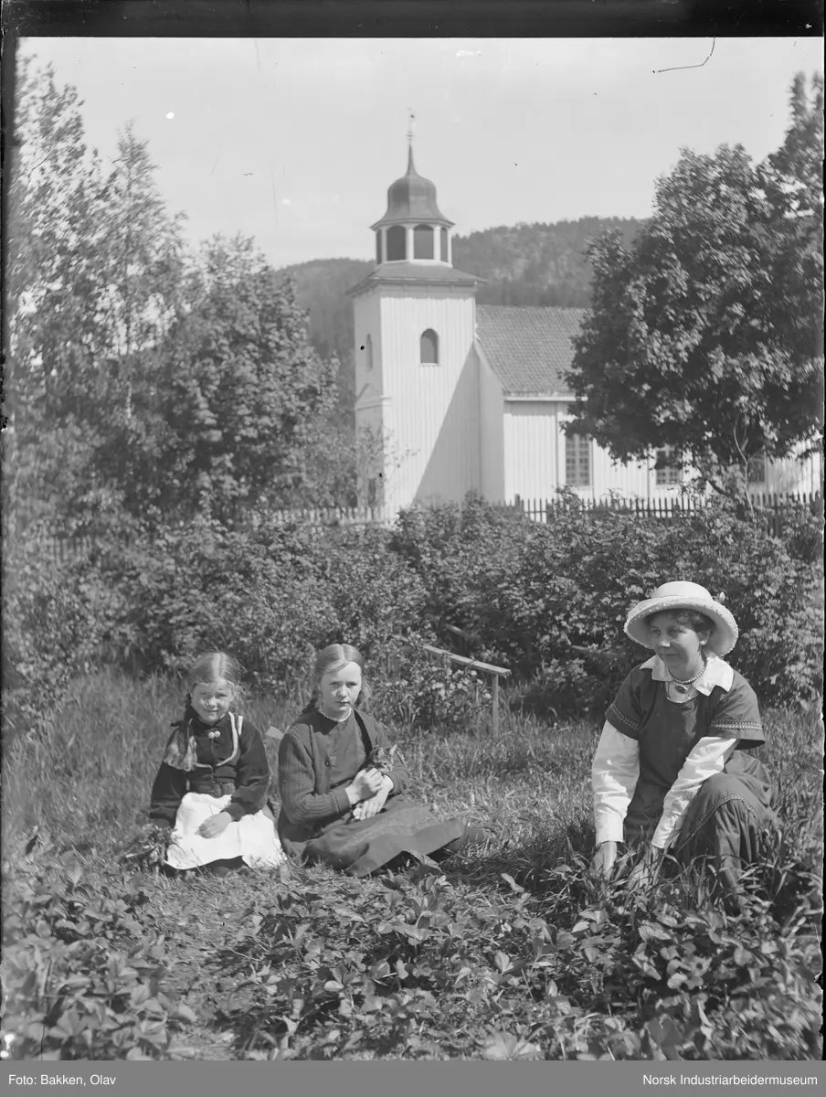 En kvinne og to barn i Prestegårdshagen. Ett av barna har en katt i ...