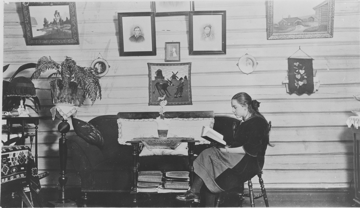 Interiør med lesende jente. Ukjent person og sted, men muligens på en ...