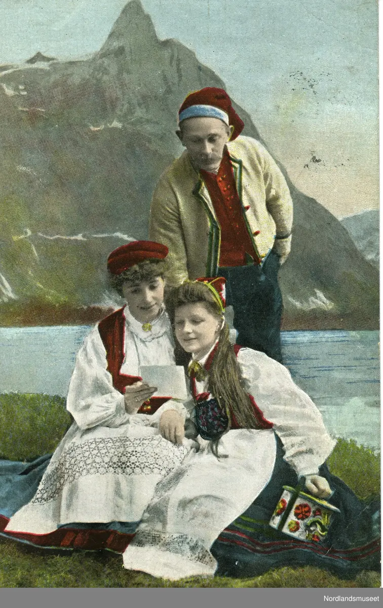 Postkort med nasjonalromantisk motiv. To kvinner i bunad sitter ute på ...