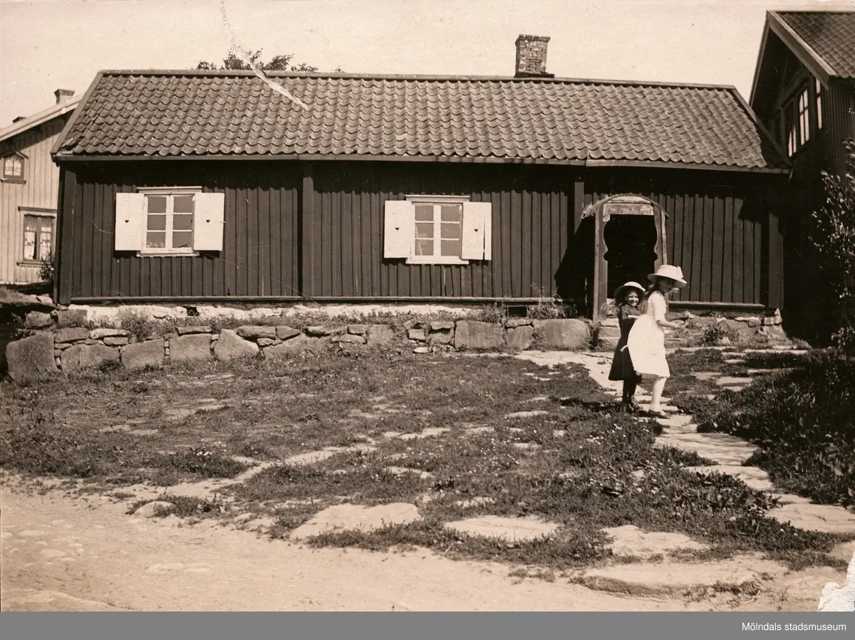 Porträtt av två flickor framför det troligen äldsta huset i Fässbergs ...