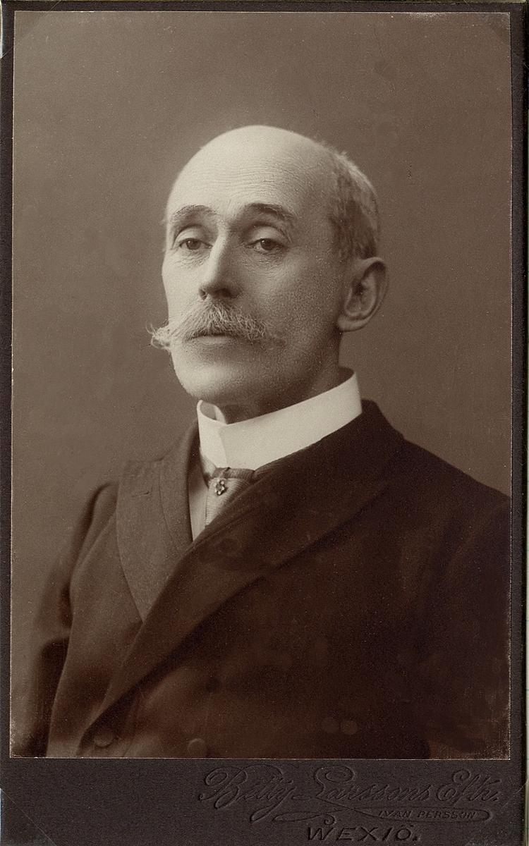 Porträttfoto av en medelålders man i mörk redingot, stärkkrage och ...