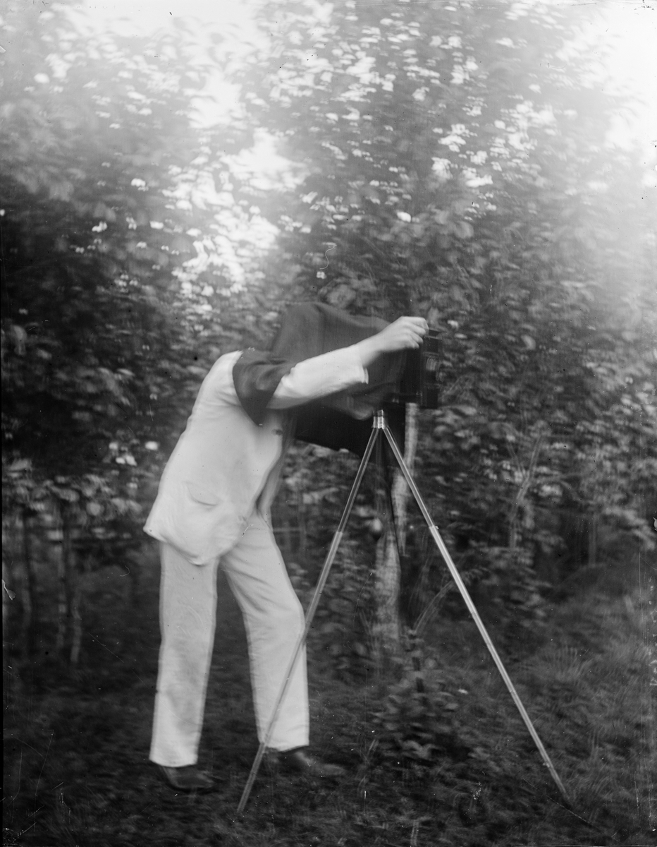 John Alinder fotograferande i trädgården, Sävasta, Altuna socken ...