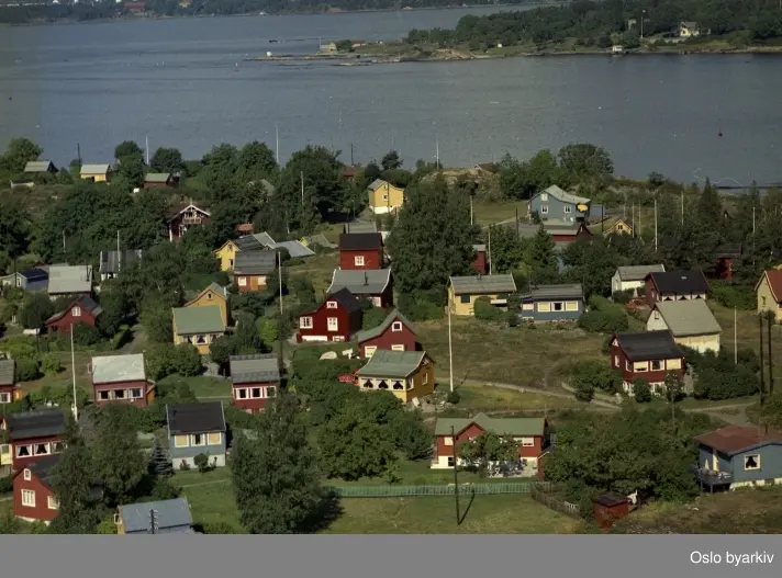 Nakholmen med de blå hyttene. Hukodden med strandrestauranten i ...